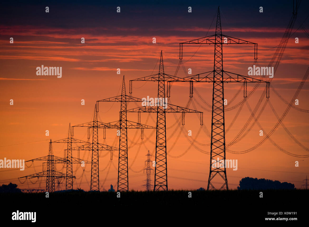 The rising sun flooding with a warm light the sky over high voltage ...
