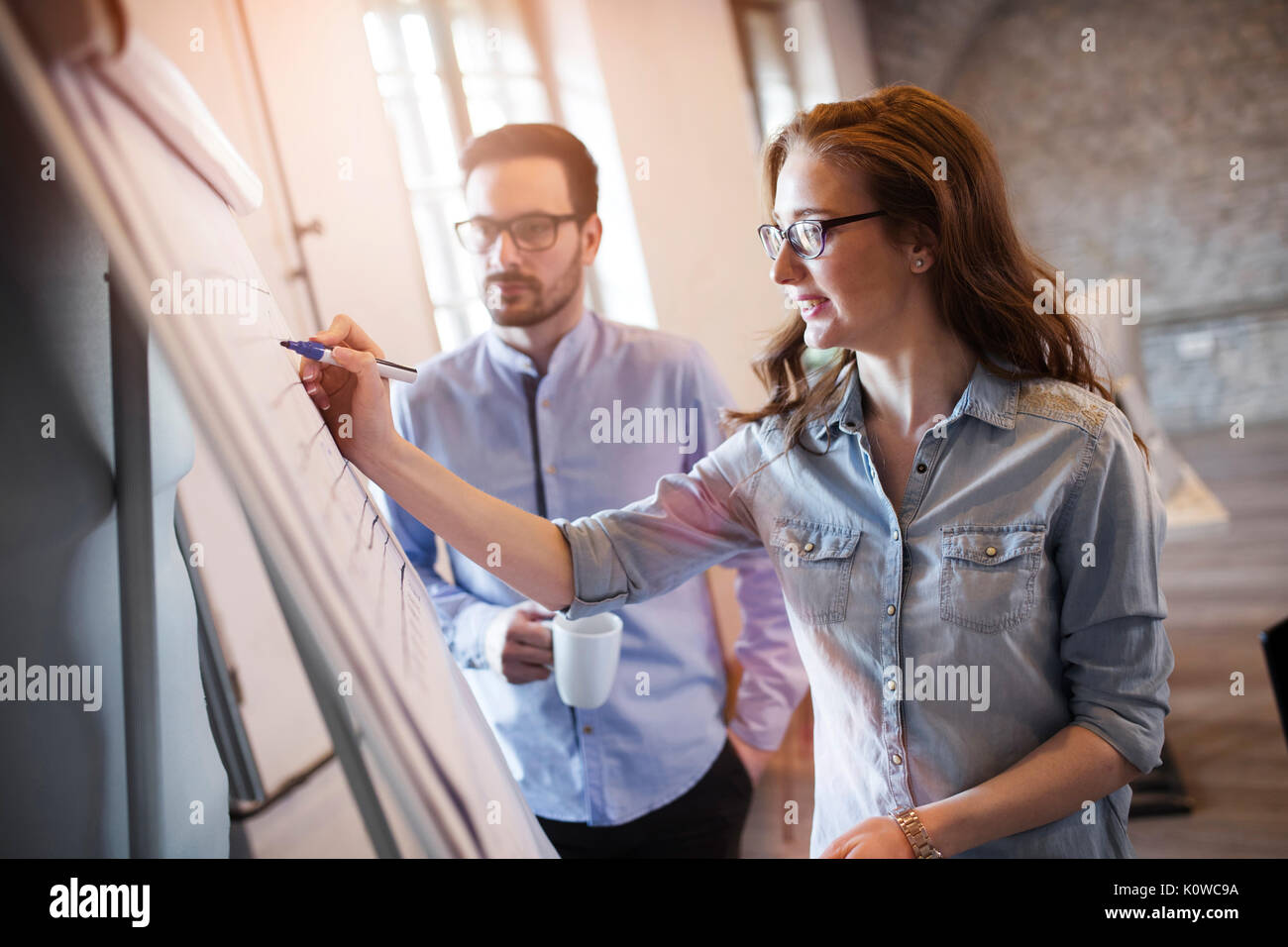 Portrait of architects discussing and drawing on board Stock Photo - Alamy