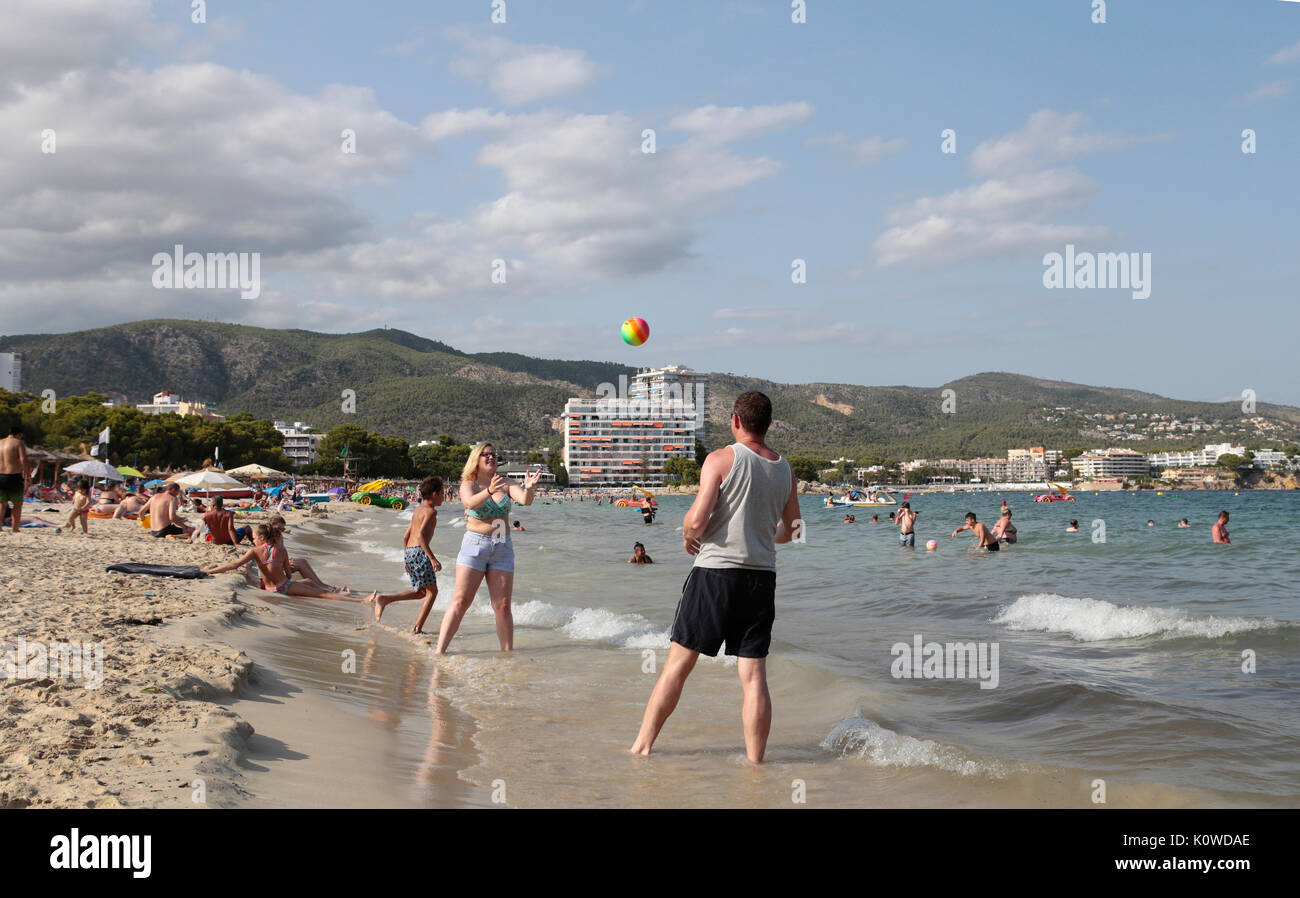 Tourists swim or enjoy marine activities as they sunbatthe in the beach ...