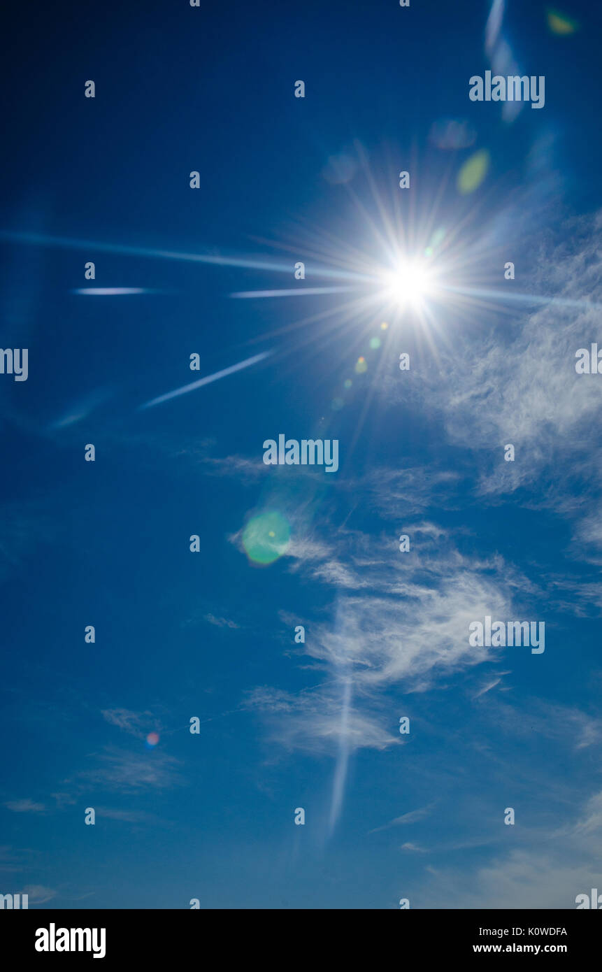 Sun with lens flare, on blue sky background. Glare from the bright sun ...