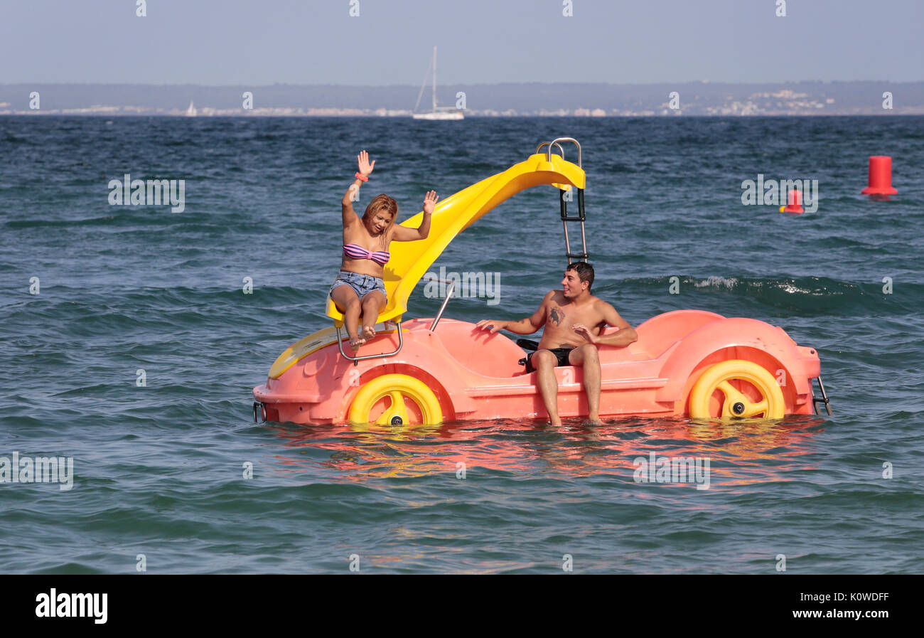 Tourists swim or enjoy marine activities as they sunbatthe in the beach ...