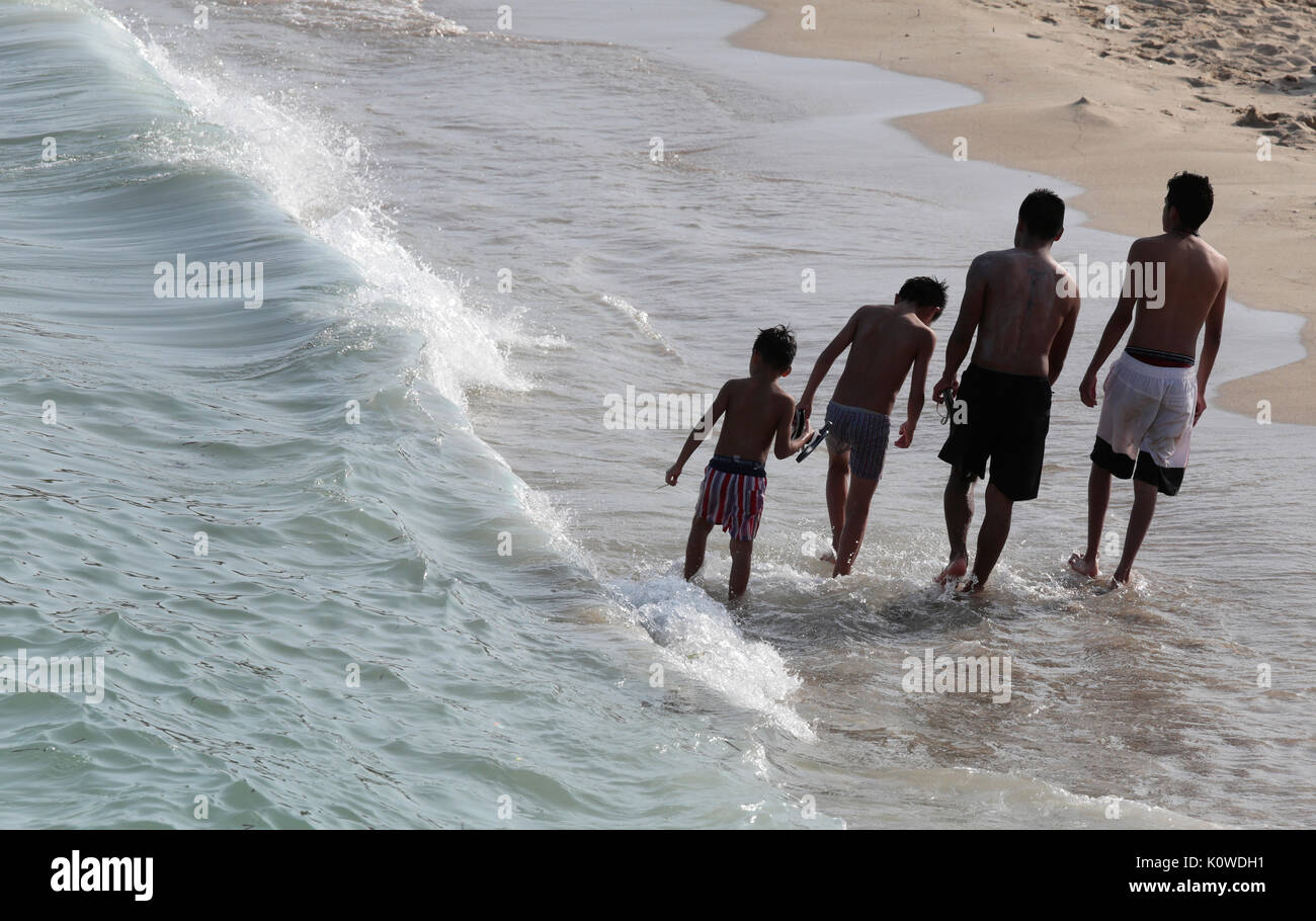 Tourists swim or enjoy marine activities as they sunbatthe in the beach ...