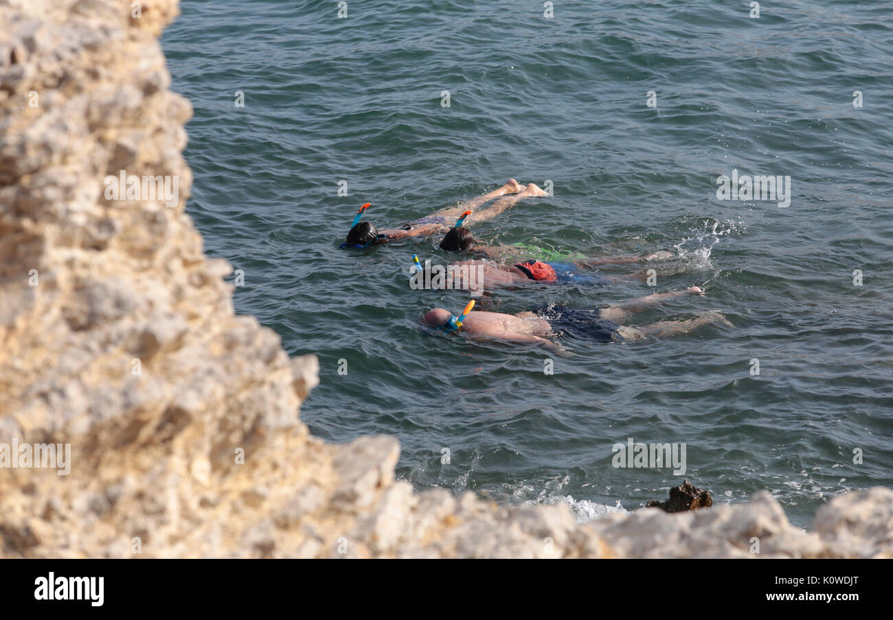 Tourists swim or enjoy marine activities as they sunbatthe in the beach ...