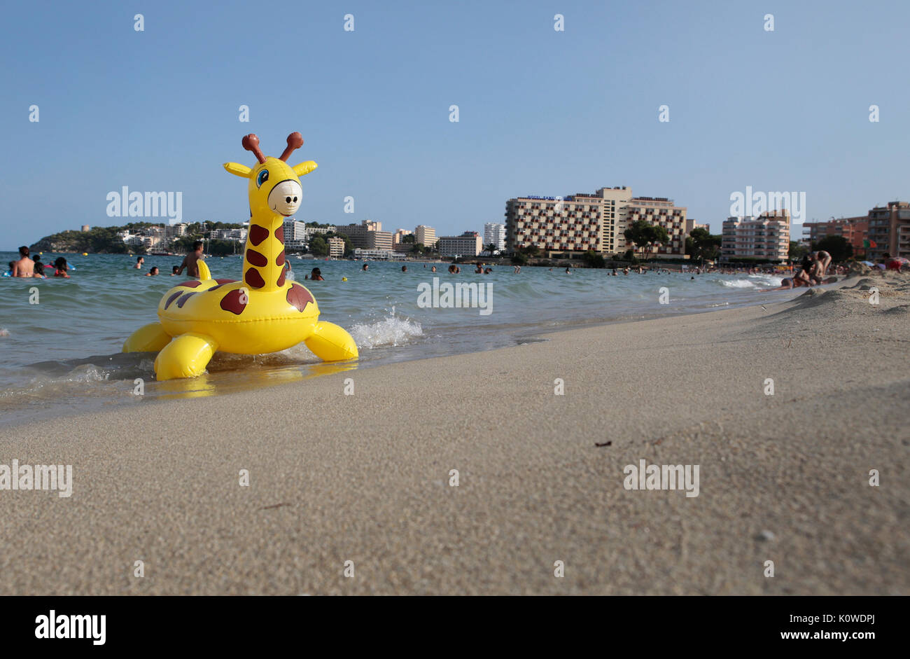 Tourists swim or enjoy marine activities as they sunbatthe in the beach ...