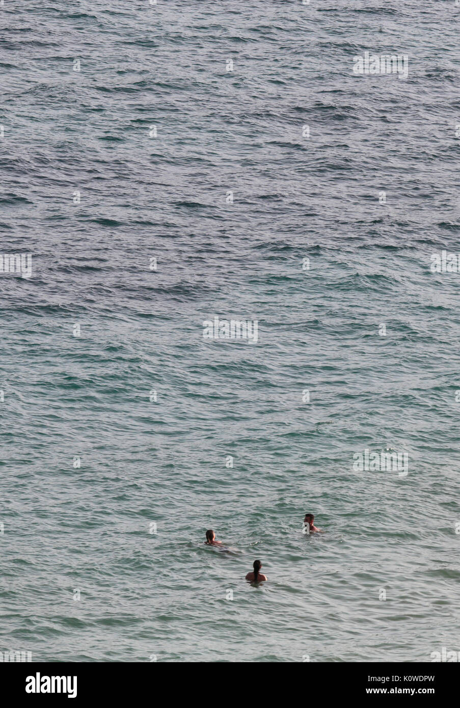 Tourists swim or enjoy marine activities as they sunbatthe in the beach ...