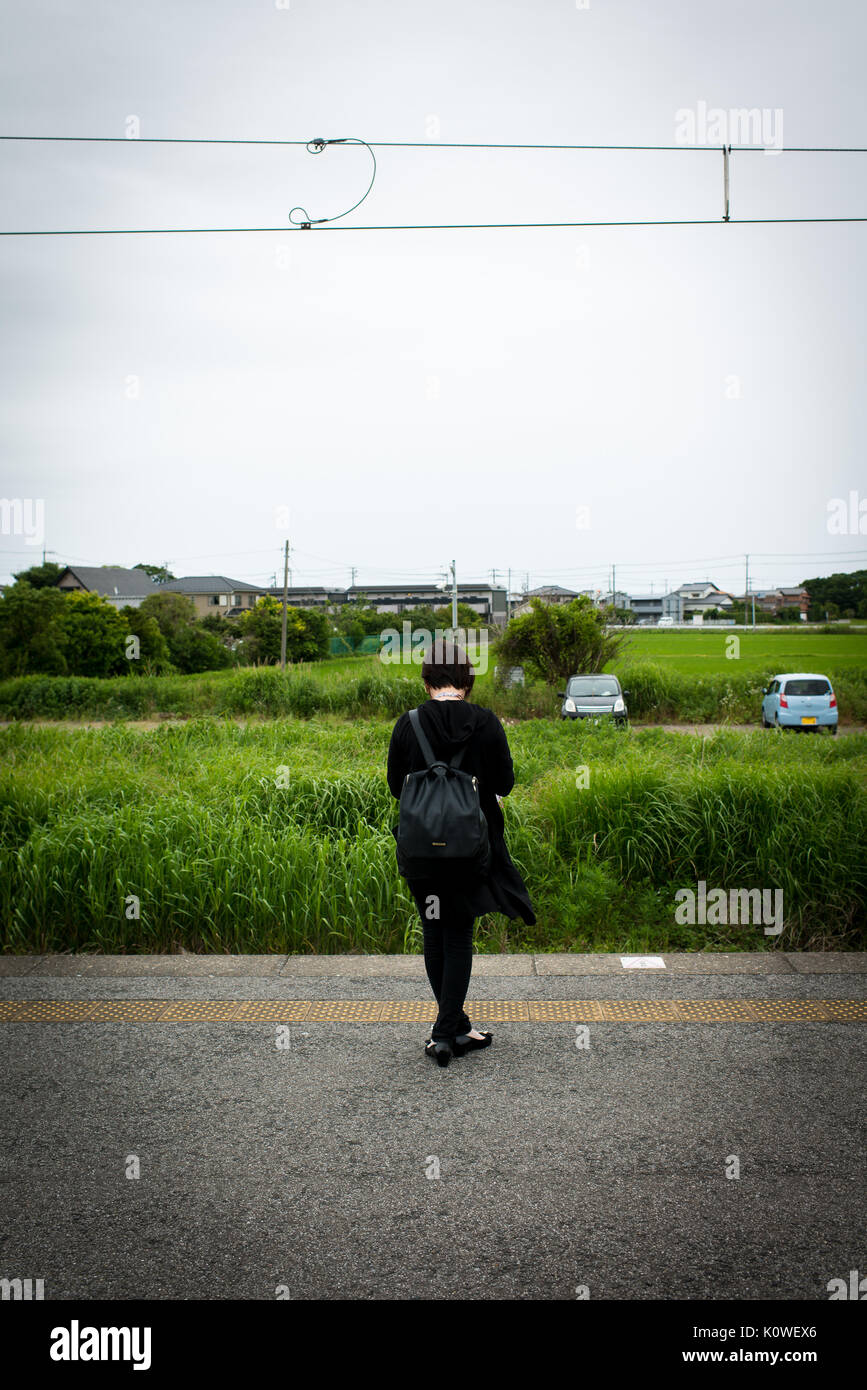 Woman standing alone on a train platform in the countryside Stock Photo ...