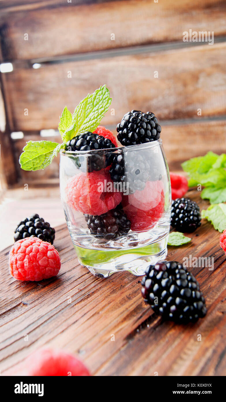 black berries and raspberries in a glass black background, selective ...