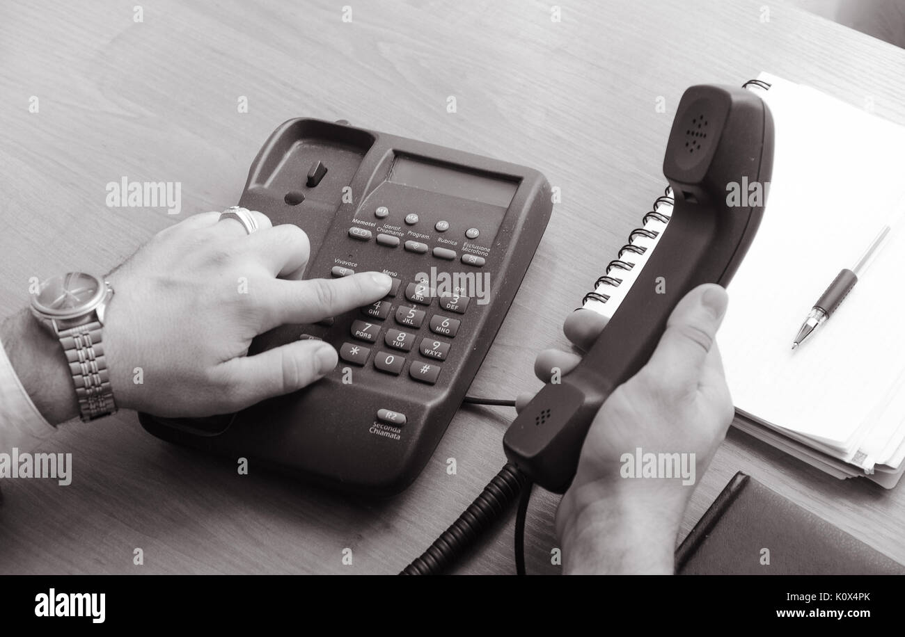 The businessman dials the number on the landline phone, holds the ...