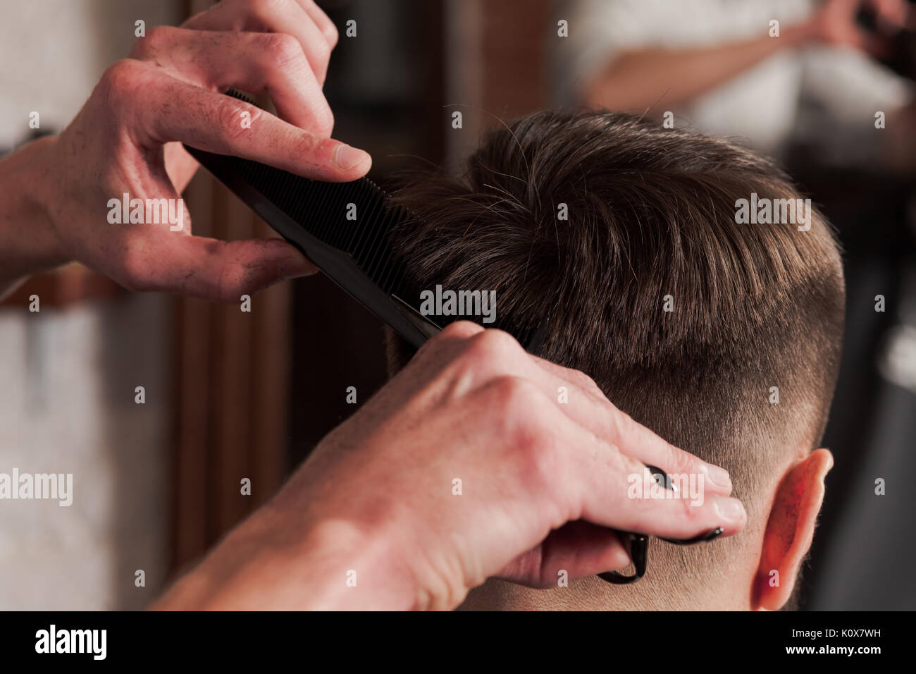 The hands of barber making haircut to young man in barbershop Stock ...