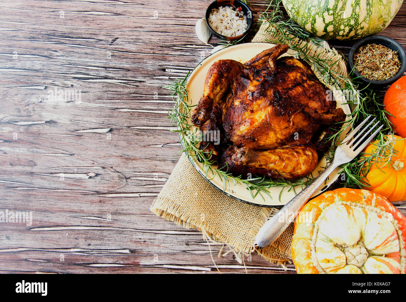 Seasonal wooden table setting with small pumpkins, baked chicken, with ...
