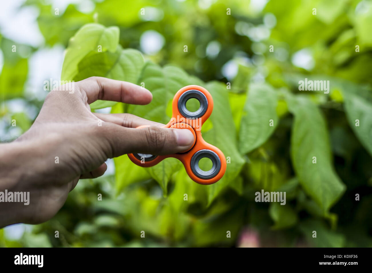 A hand holding orange fidget spinner Stock Photo - Alamy