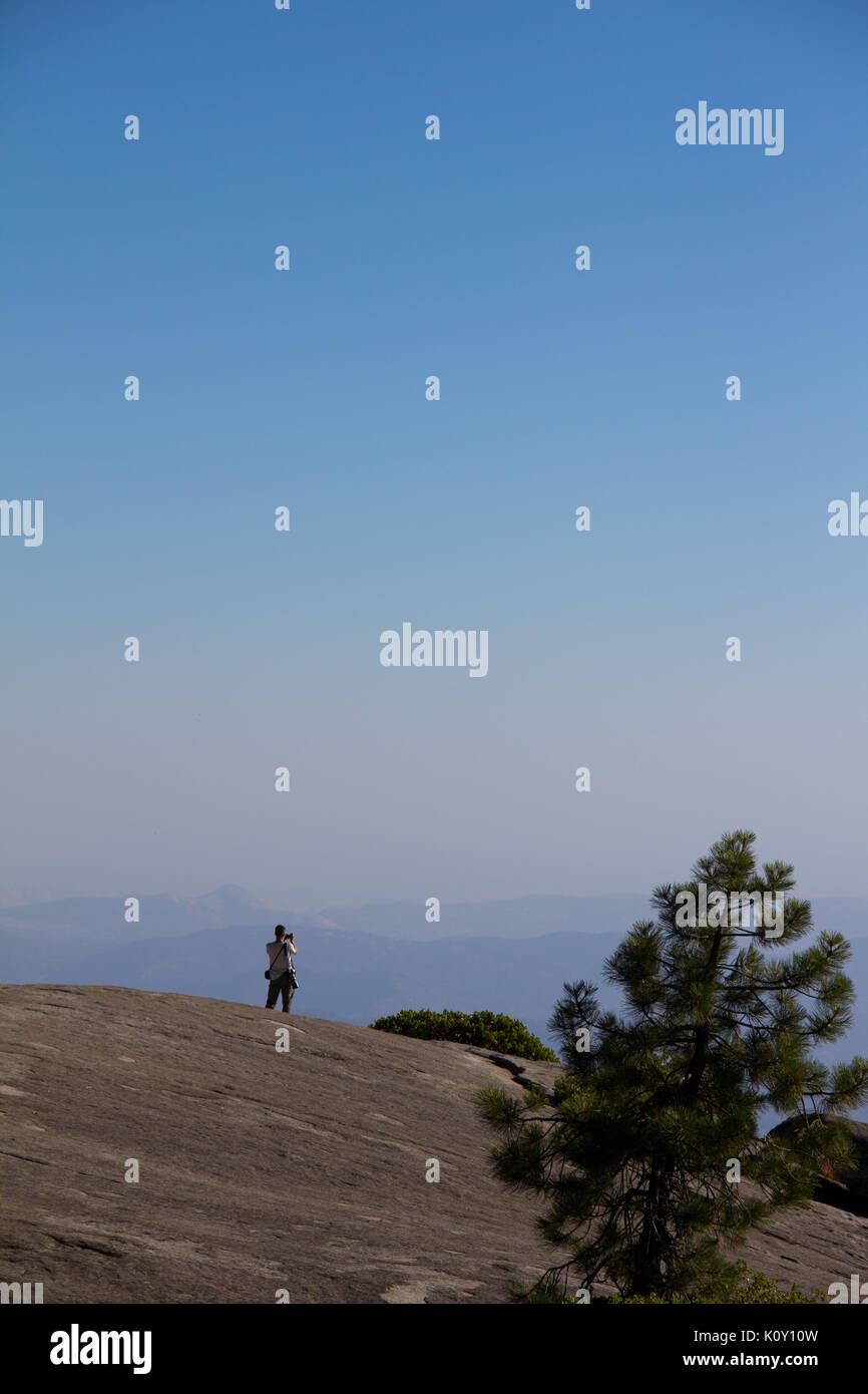 A photographer stands atop Beetle Rock, overlooking the scenery, which ...