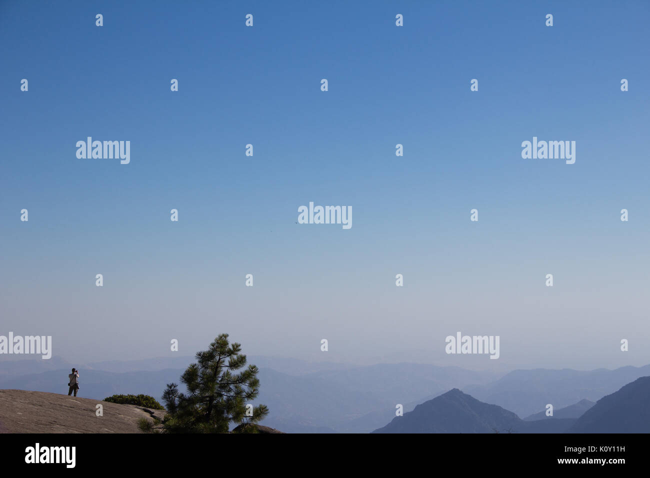 A photographer stands atop Beetle Rock, overlooking the scenery, which ...