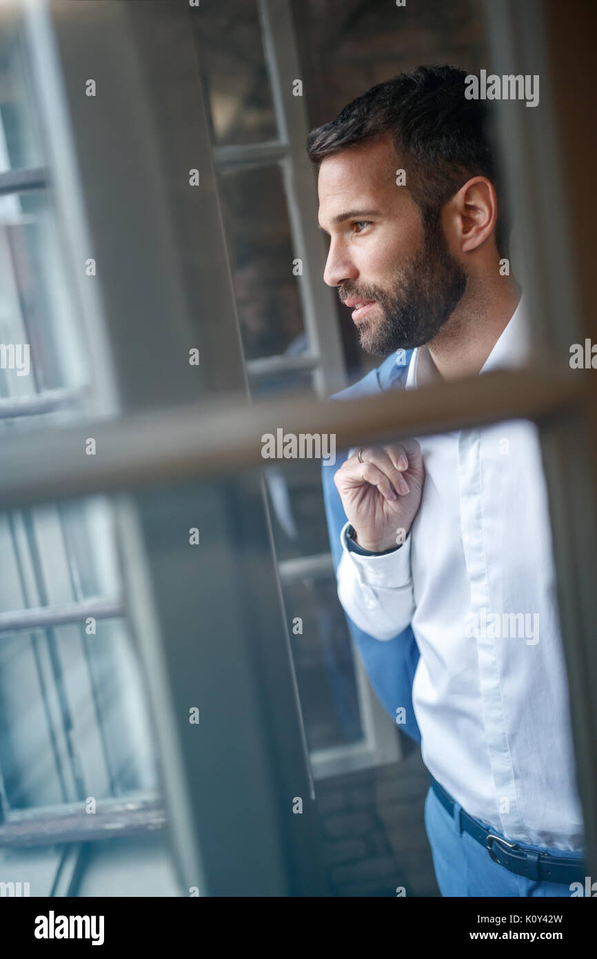Handsome man in studio looking through open window Stock Photo - Alamy