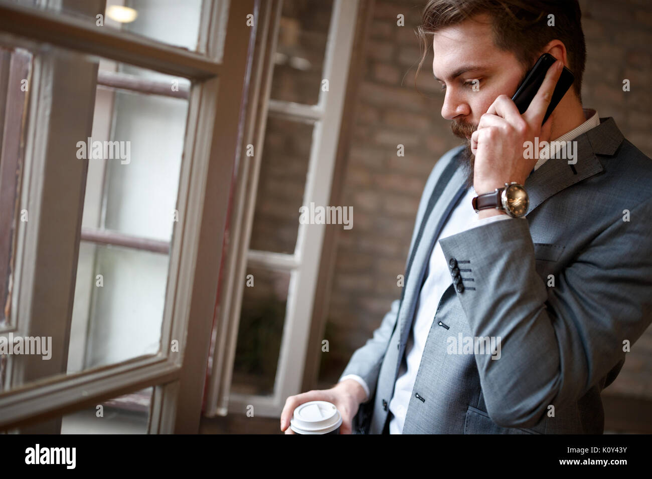 Boss in company near window talking on cell phone with business partner ...