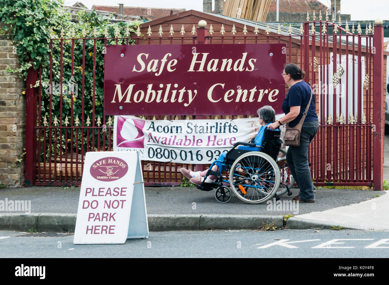 An elderly 97 year old woman in a wheelchair with her carer or ...