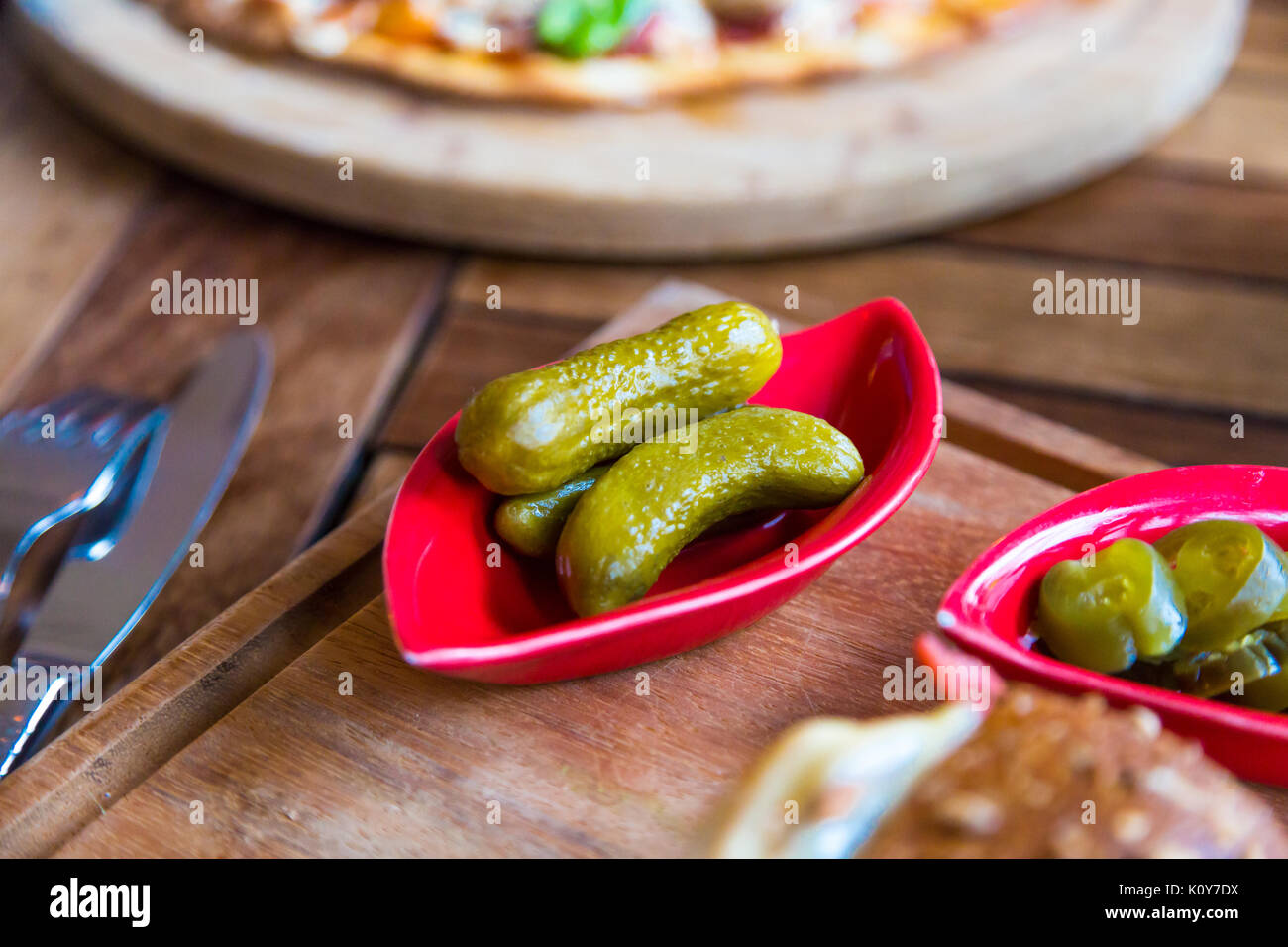 Close up detailed view of tasty pickled gherkins served on a red plate ...