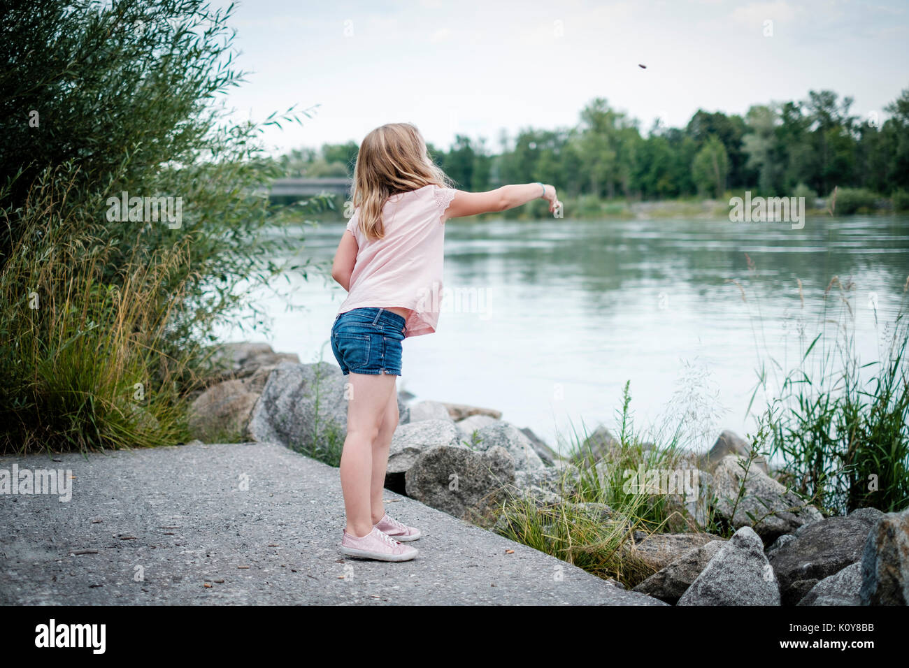 Little girl throwing stones into a river Stock Photo - Alamy