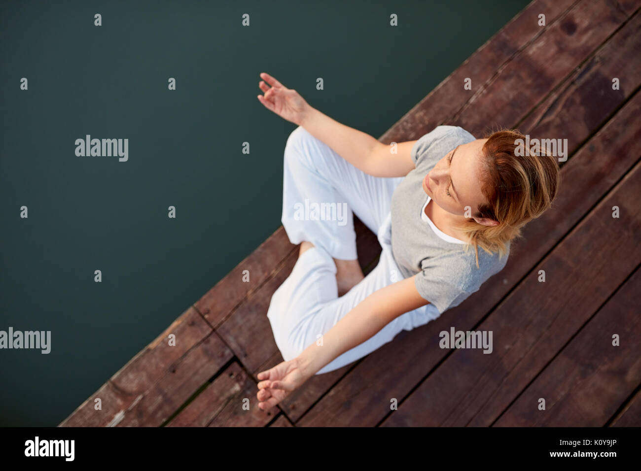 Top view of girl in yoga position near water on dock Stock Photo - Alamy