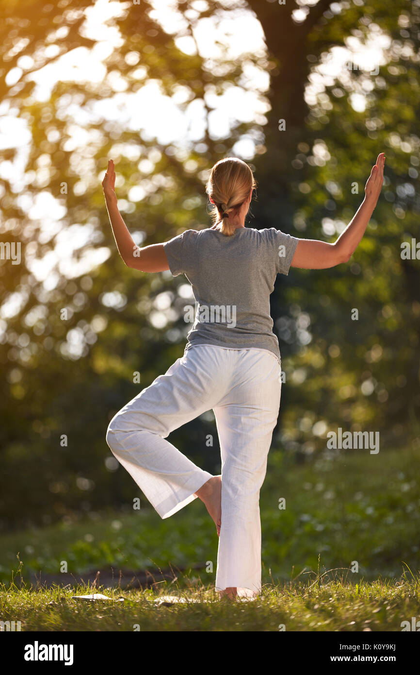 Woman exercising body balance exercises in forest, back view Stock ...
