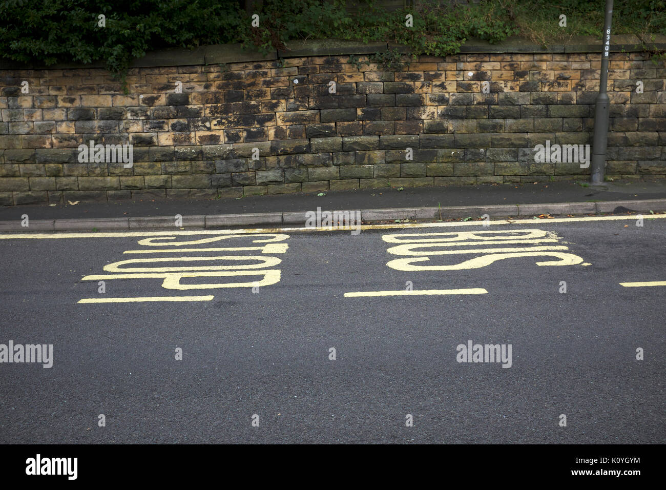 Markings on the road indicating the location of a bus stop in New Mills ...