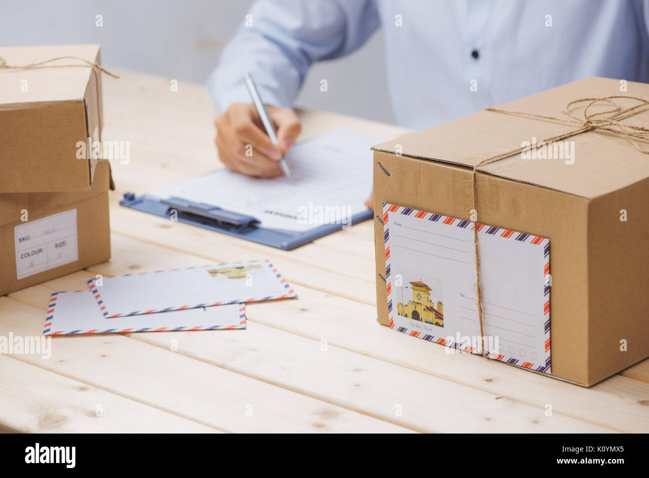 Courier making notes in delivery receipt among parcels at table Stock ...