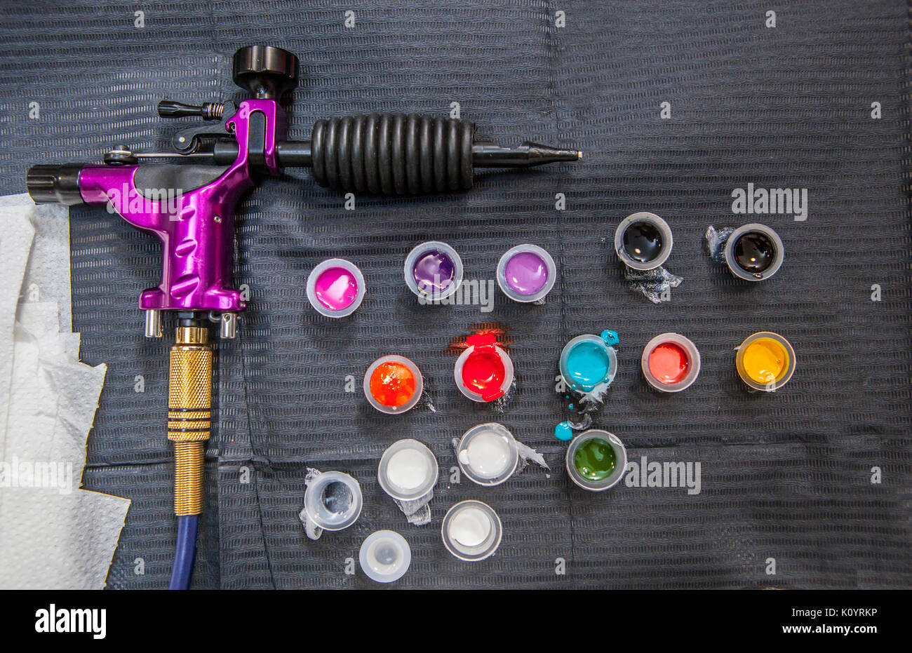 Tattoo artist table with several small cups and gun ink machine ...