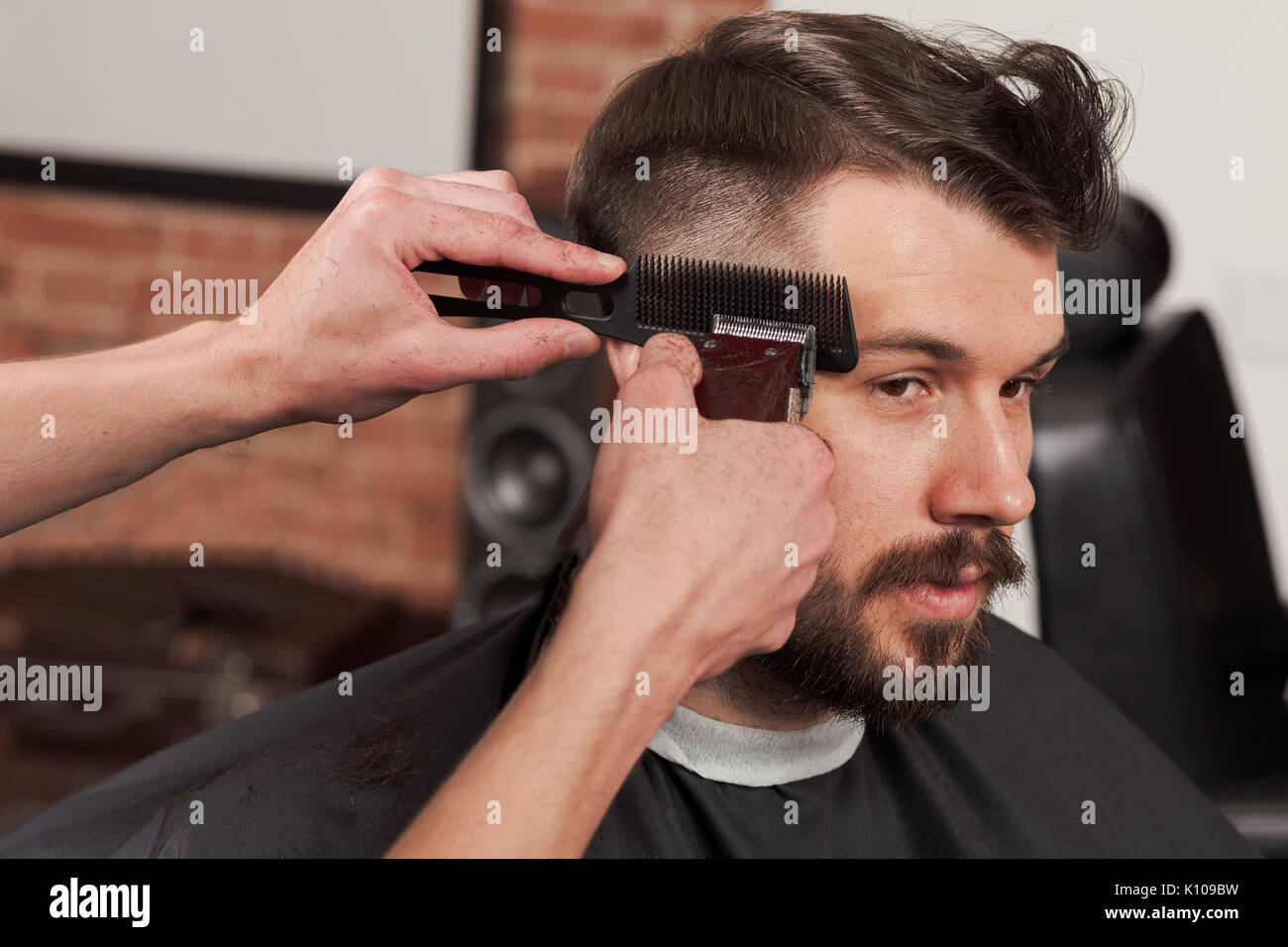 The hands of barber making haircut to young man in barbershop Stock ...