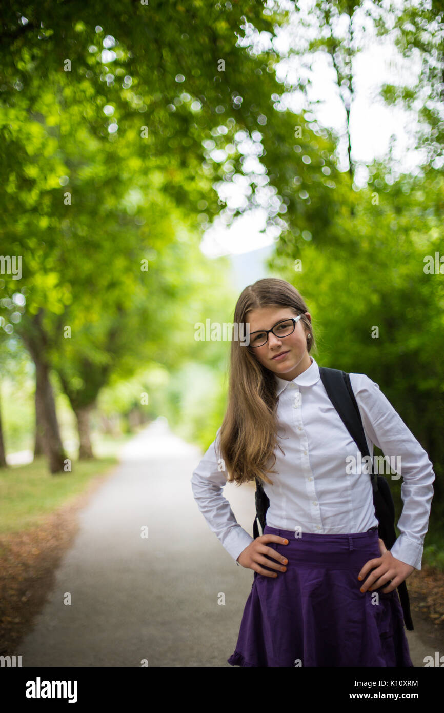 Pretty blonde school girl child posing in nature wearing white shirt ...