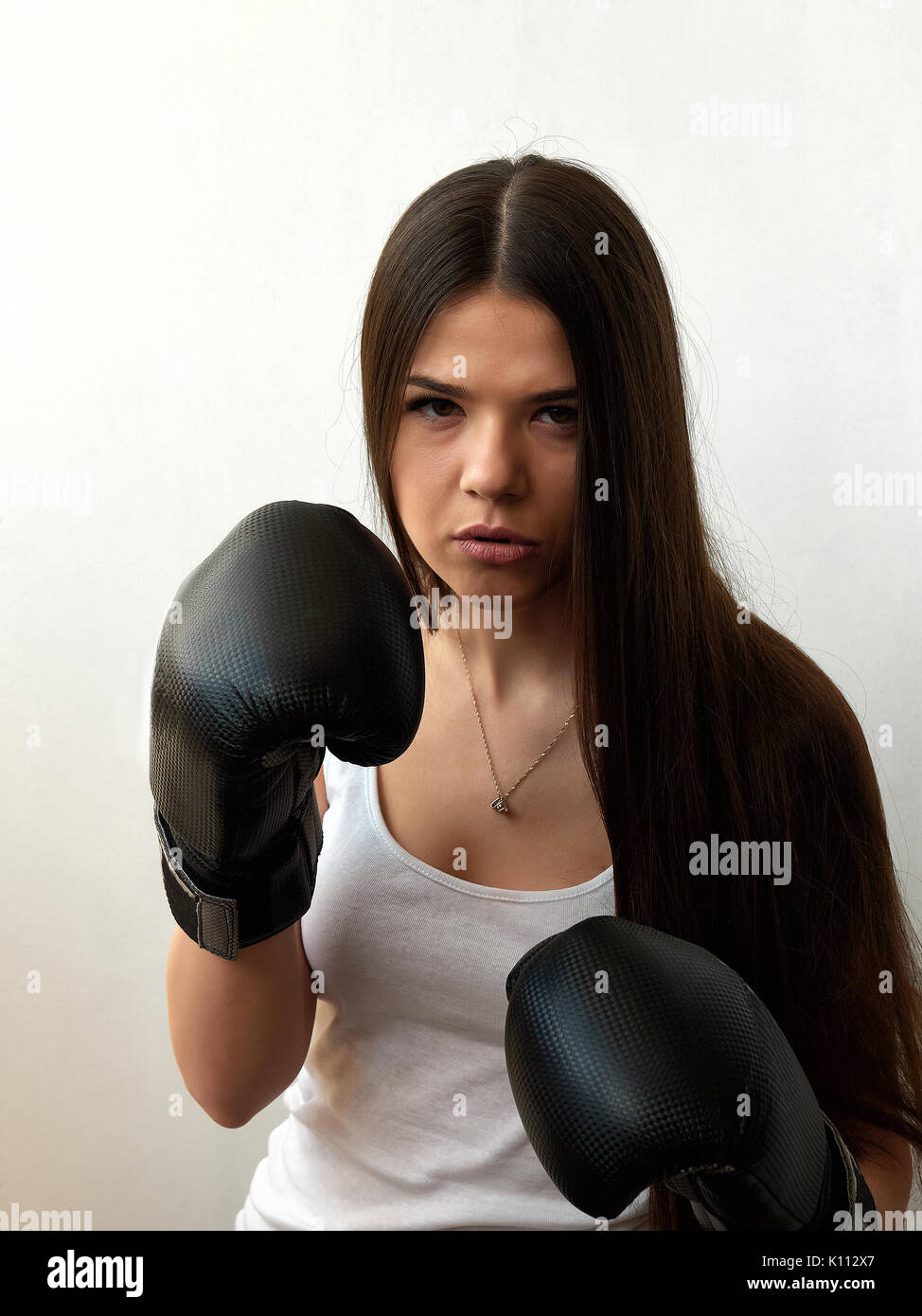 A boxer girl during boxing exercises with black gloves. White ...