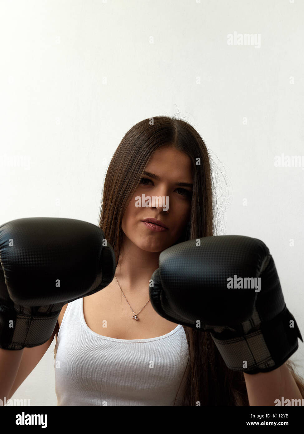 A boxer girl during boxing exercises with black gloves. White ...