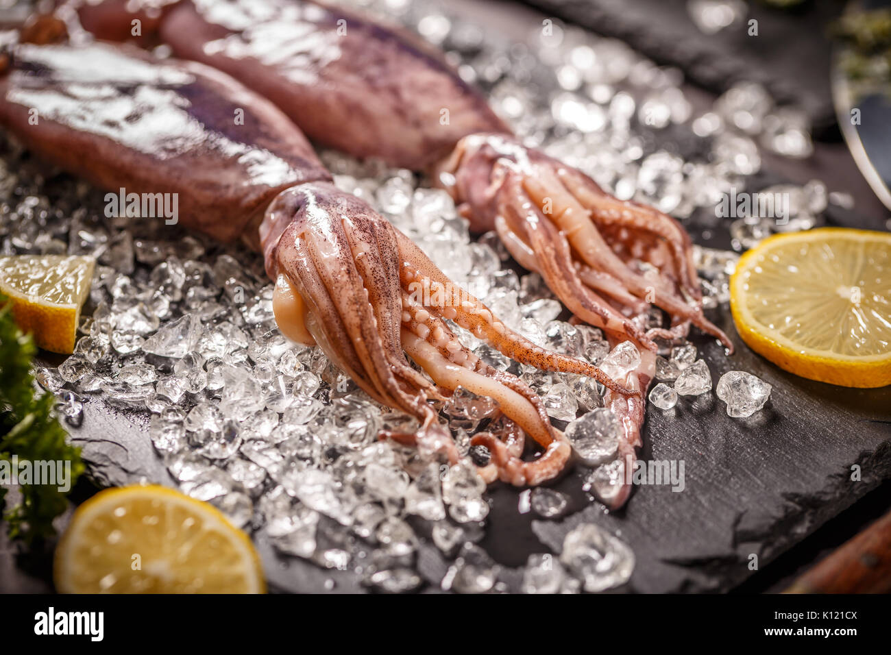 Fresh raw squid with crushed ice on black slate Stock Photo - Alamy