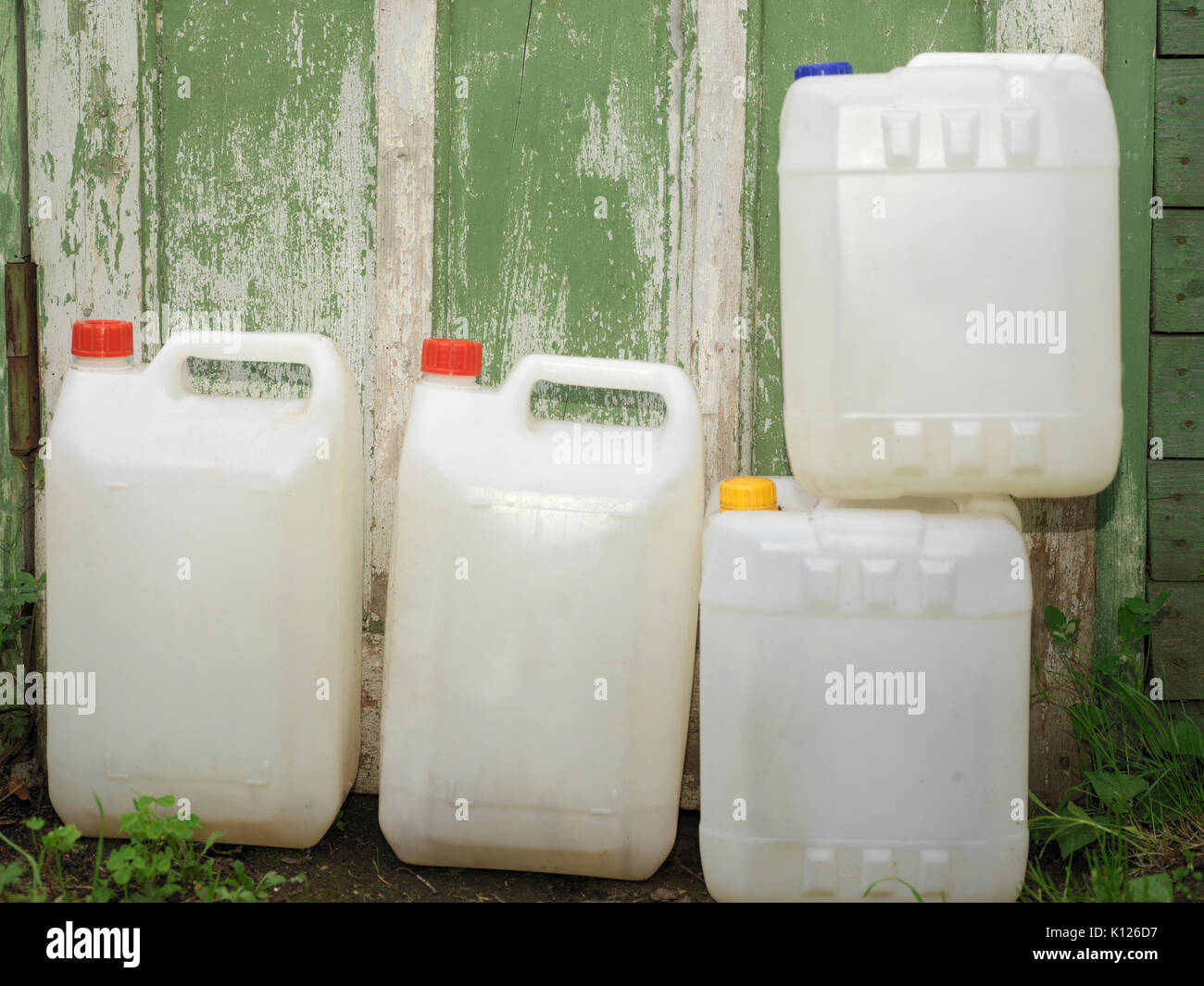 Platic canisters with water or other liquid next to the wooden barn ...