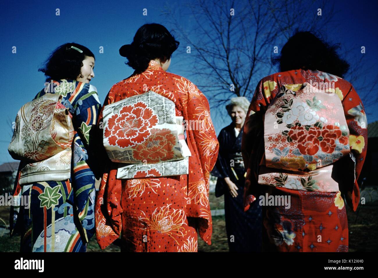 Three Japanese woman in colorful kimonos viewed from behind, speaking ...