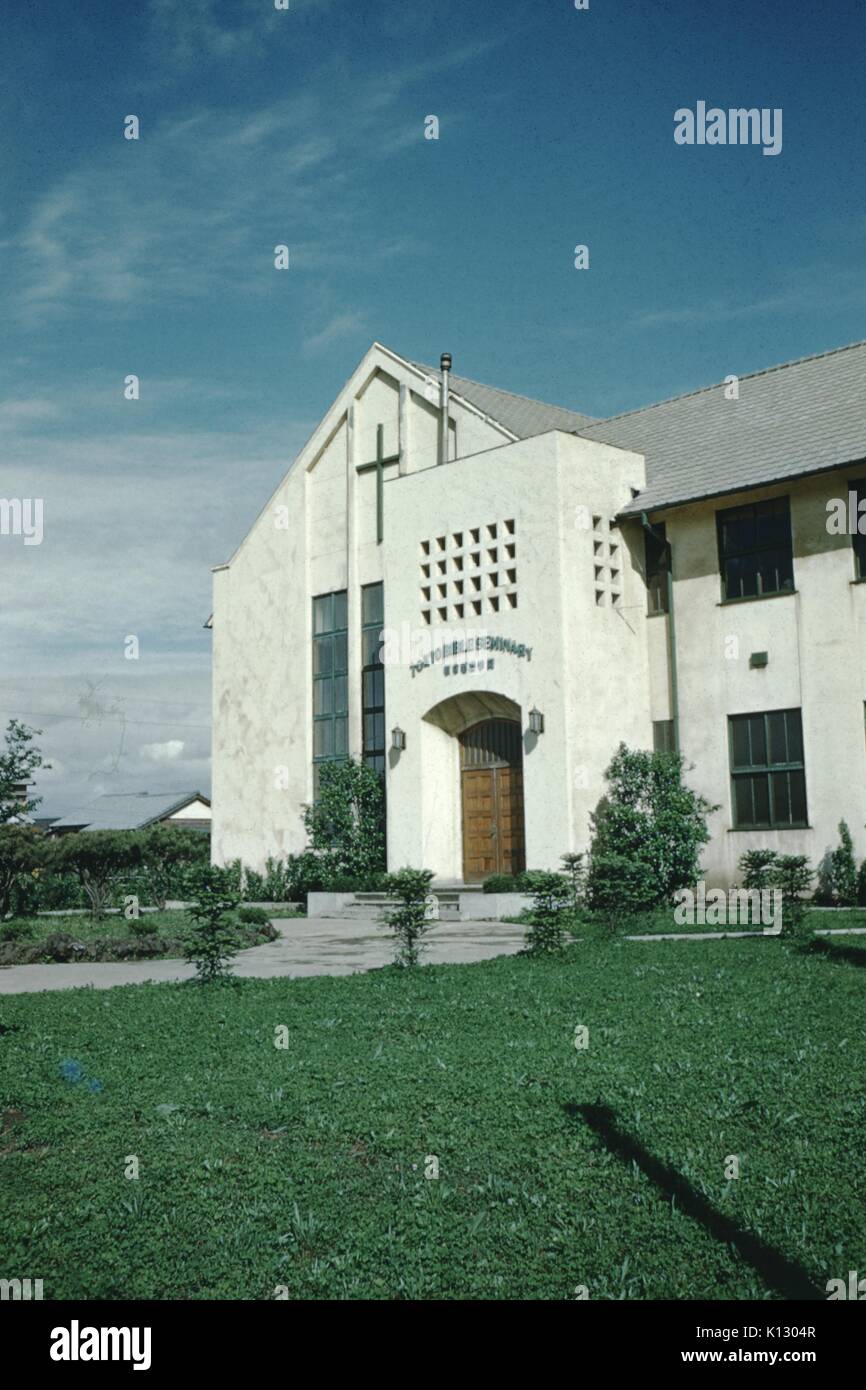 White stone building with cross, on a large green lawn, against a blue ...