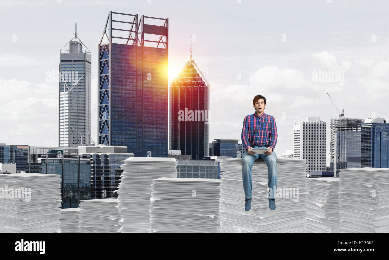 Attractive man sitting on pile of paper documents Stock Photo - Alamy