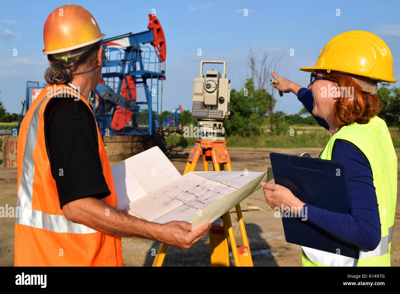 Two surveyors at work and crude oil pump in background Stock Photo - Alamy