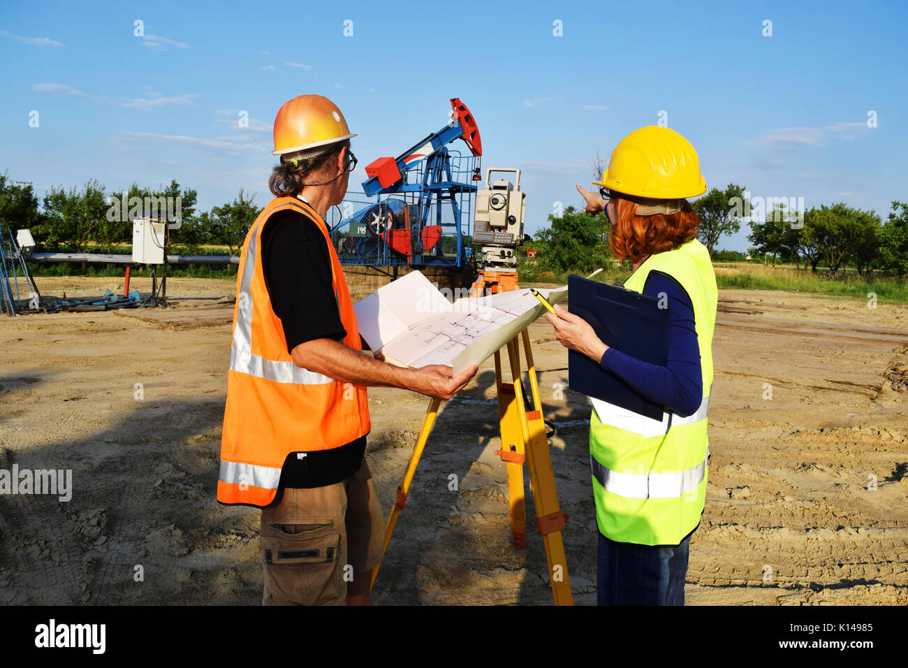 Two surveyors at work and crude oil pump in background Stock Photo - Alamy