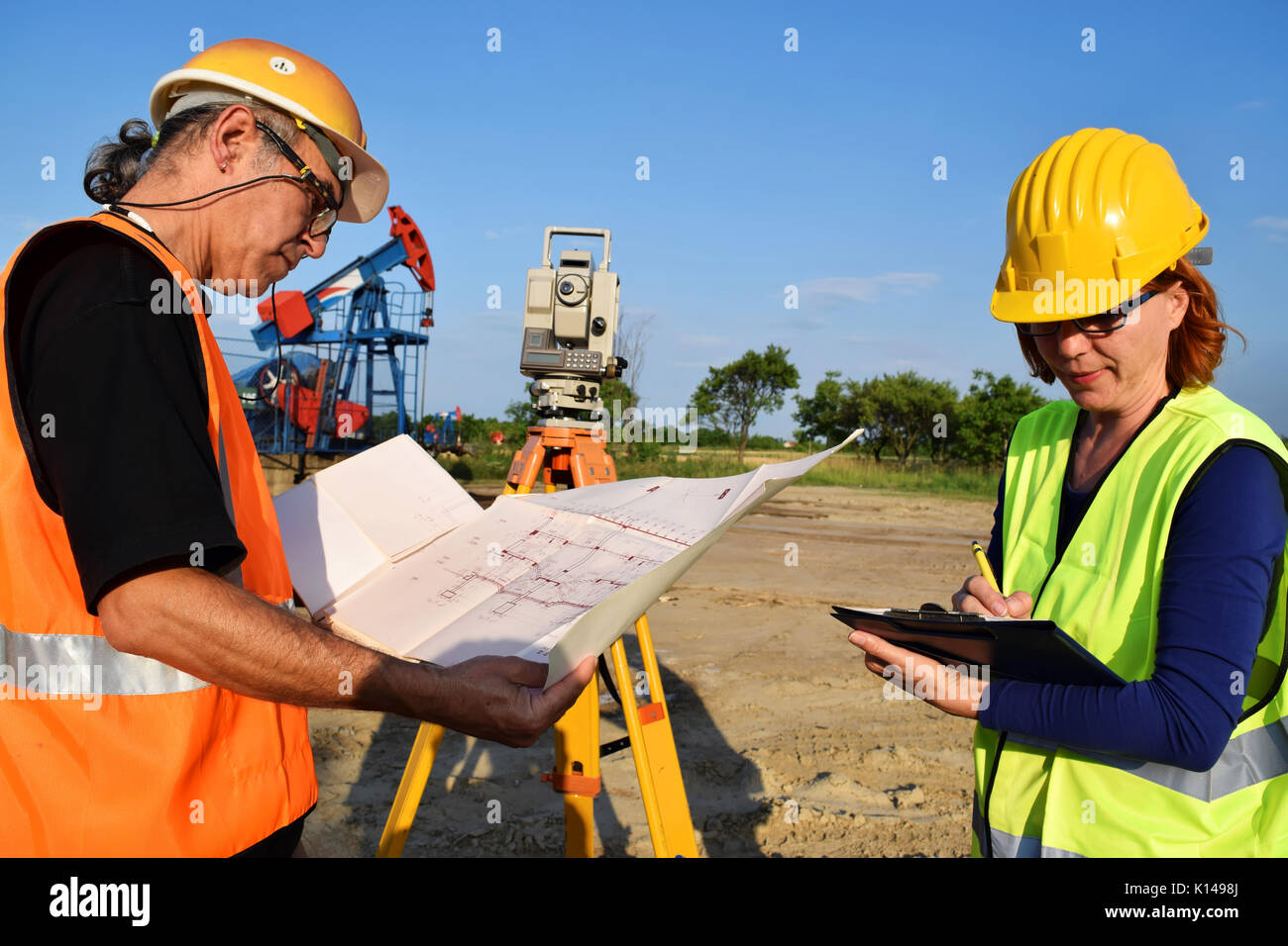 Two surveyors at work and crude oil pump in background Stock Photo - Alamy