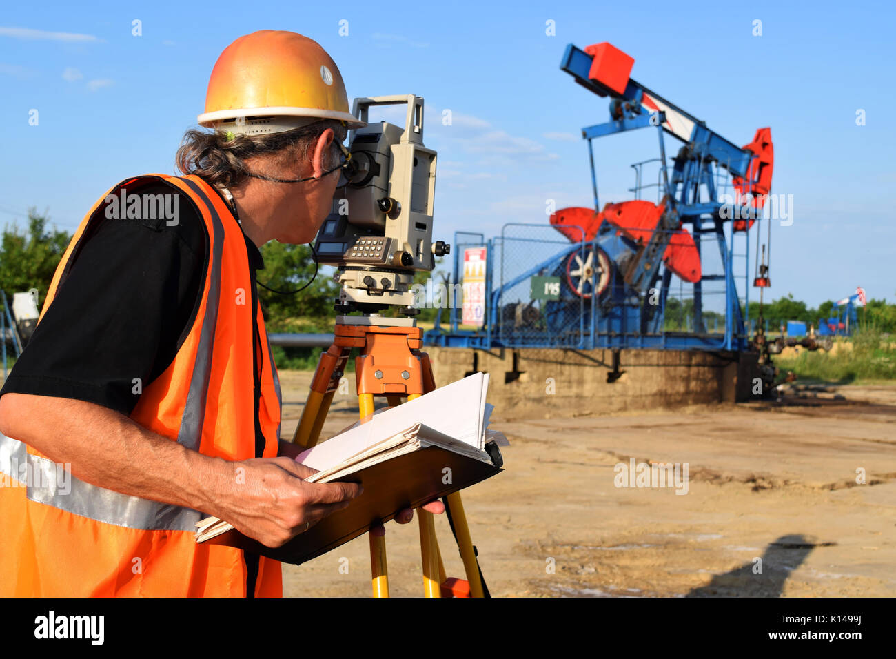 Surveyor at work and crude oil pump in background Stock Photo - Alamy