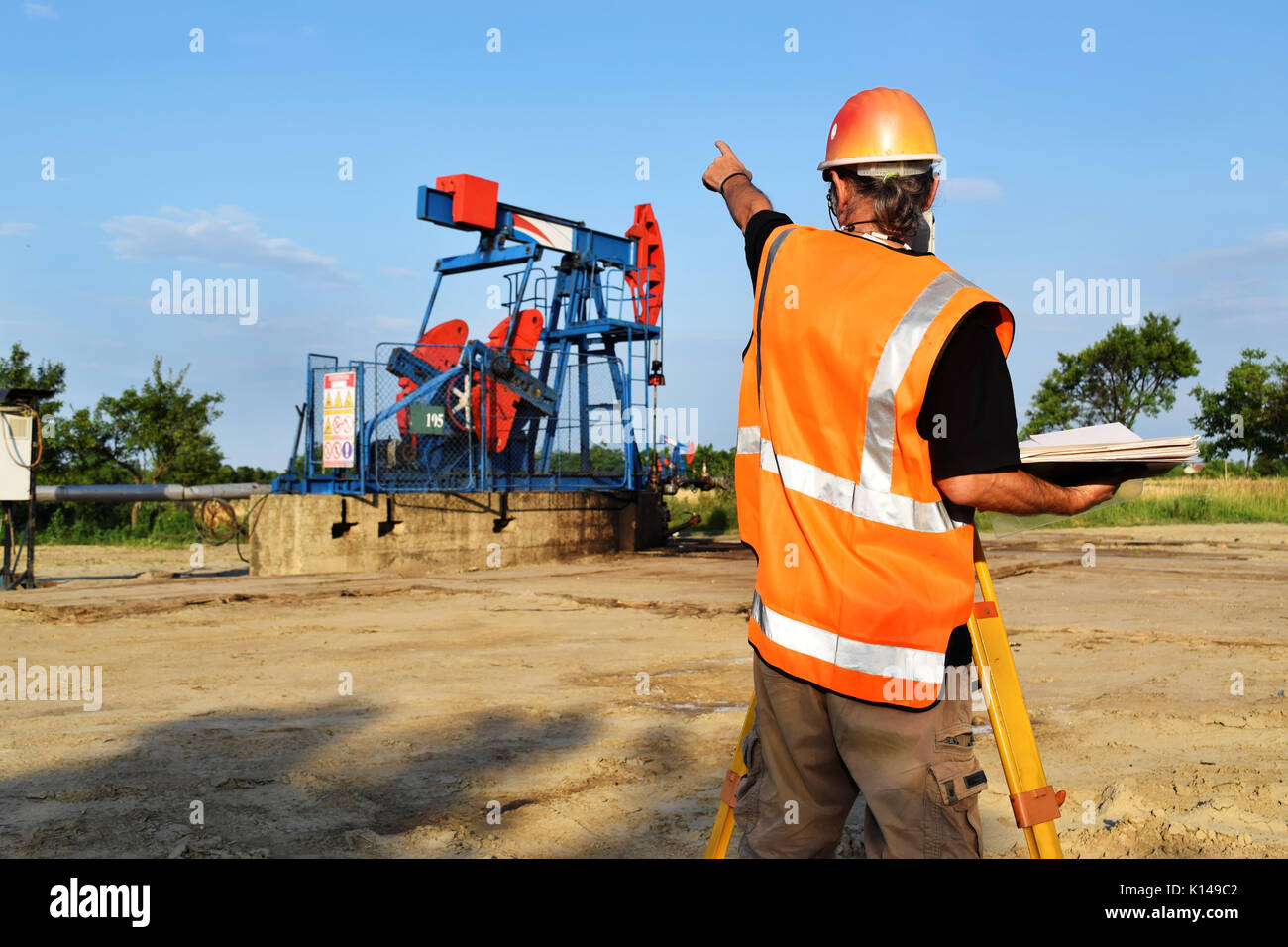 Surveyor at work and crude oil pump in background Stock Photo - Alamy