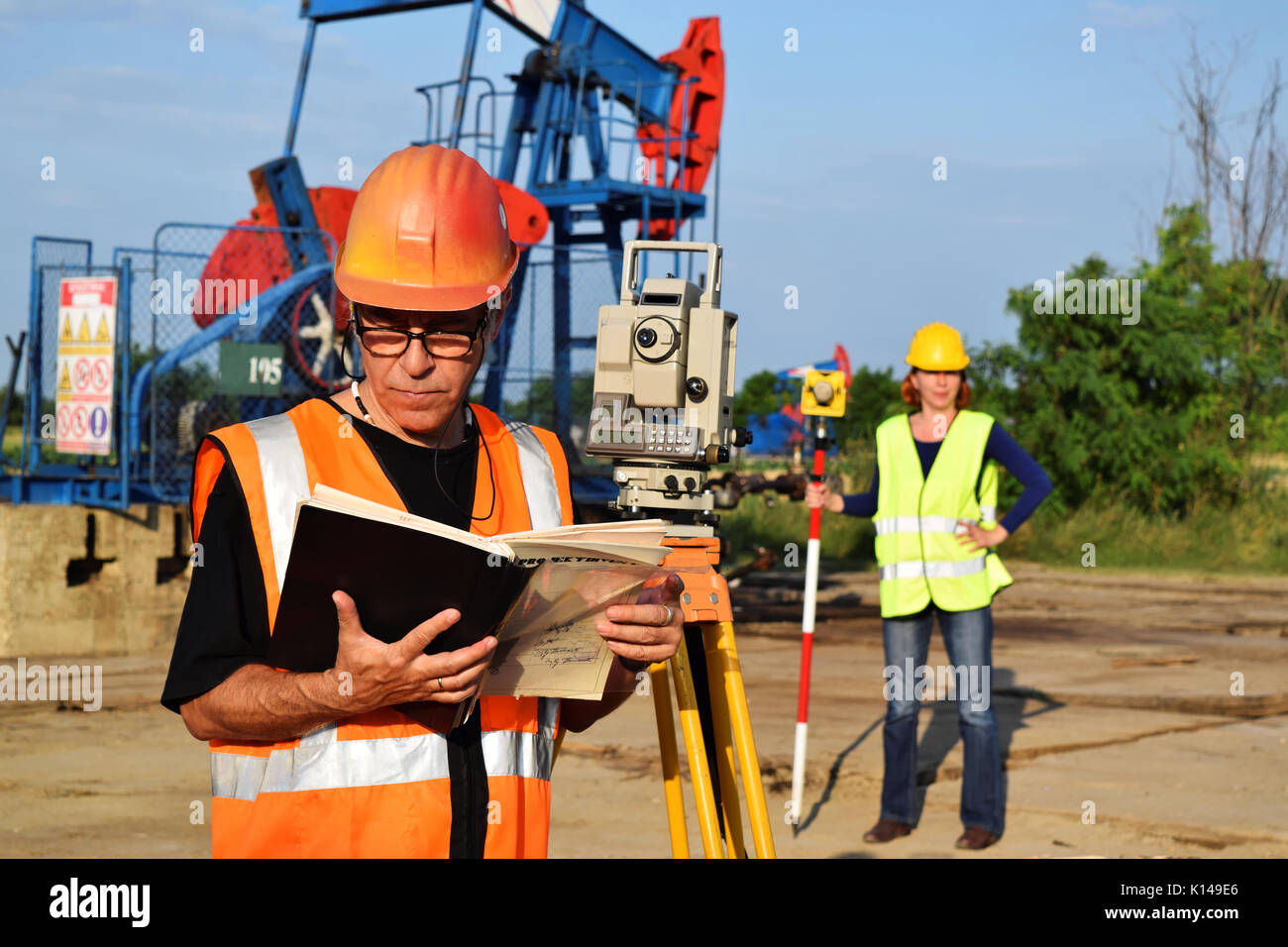 Two surveyors at work and crude oil pump in background Stock Photo - Alamy