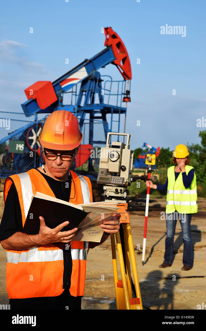 Two surveyors at work and crude oil pump in background Stock Photo - Alamy
