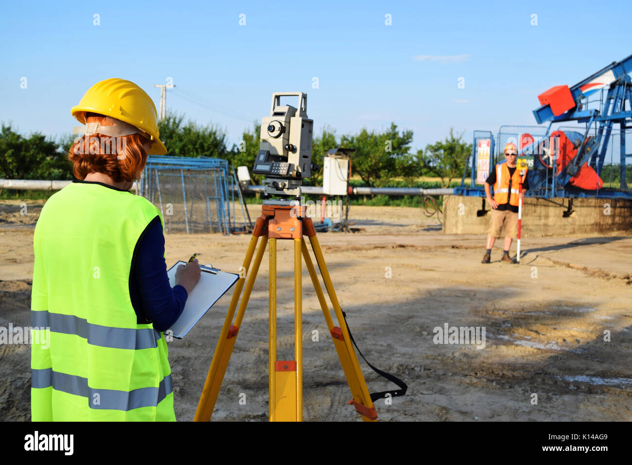 Two surveyors at work and crude oil pump in background Stock Photo - Alamy