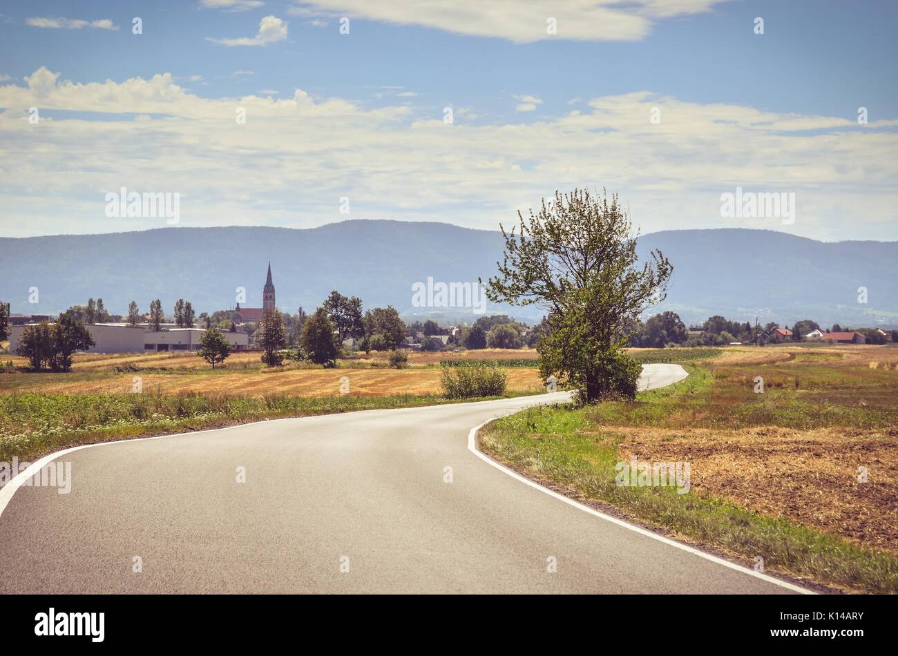 Summer rural landscape. Asphalt road with mountains and village in the ...