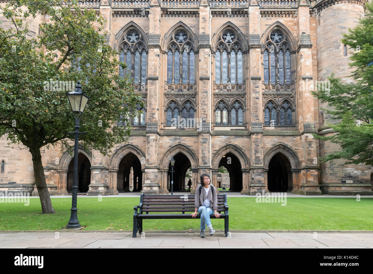A girl sits on a bench in the courtyard of the University of Glasgow Stock Photo - Alamy