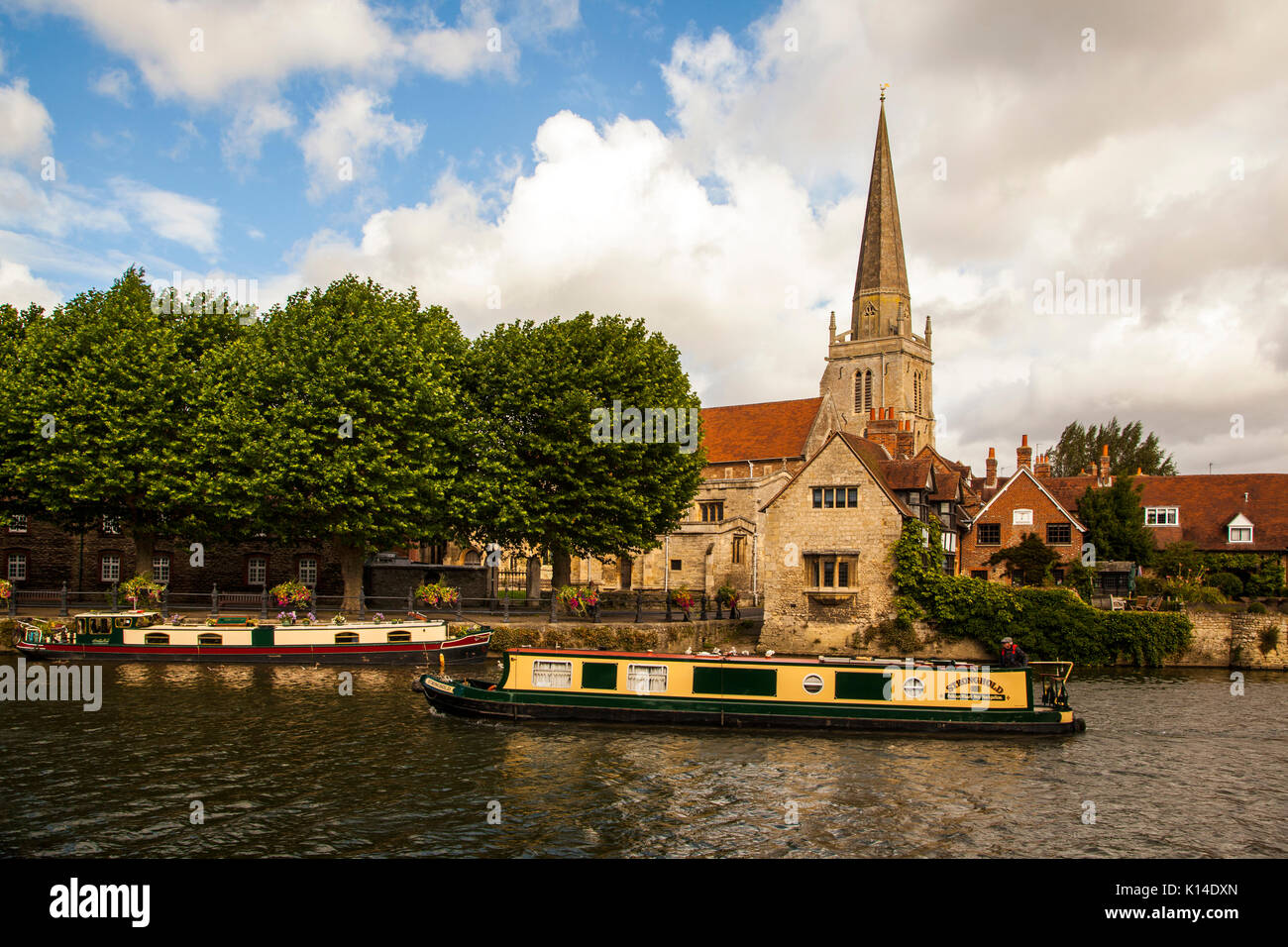 Canal narrowboat on the river Thames passing St Helen's church and St ...