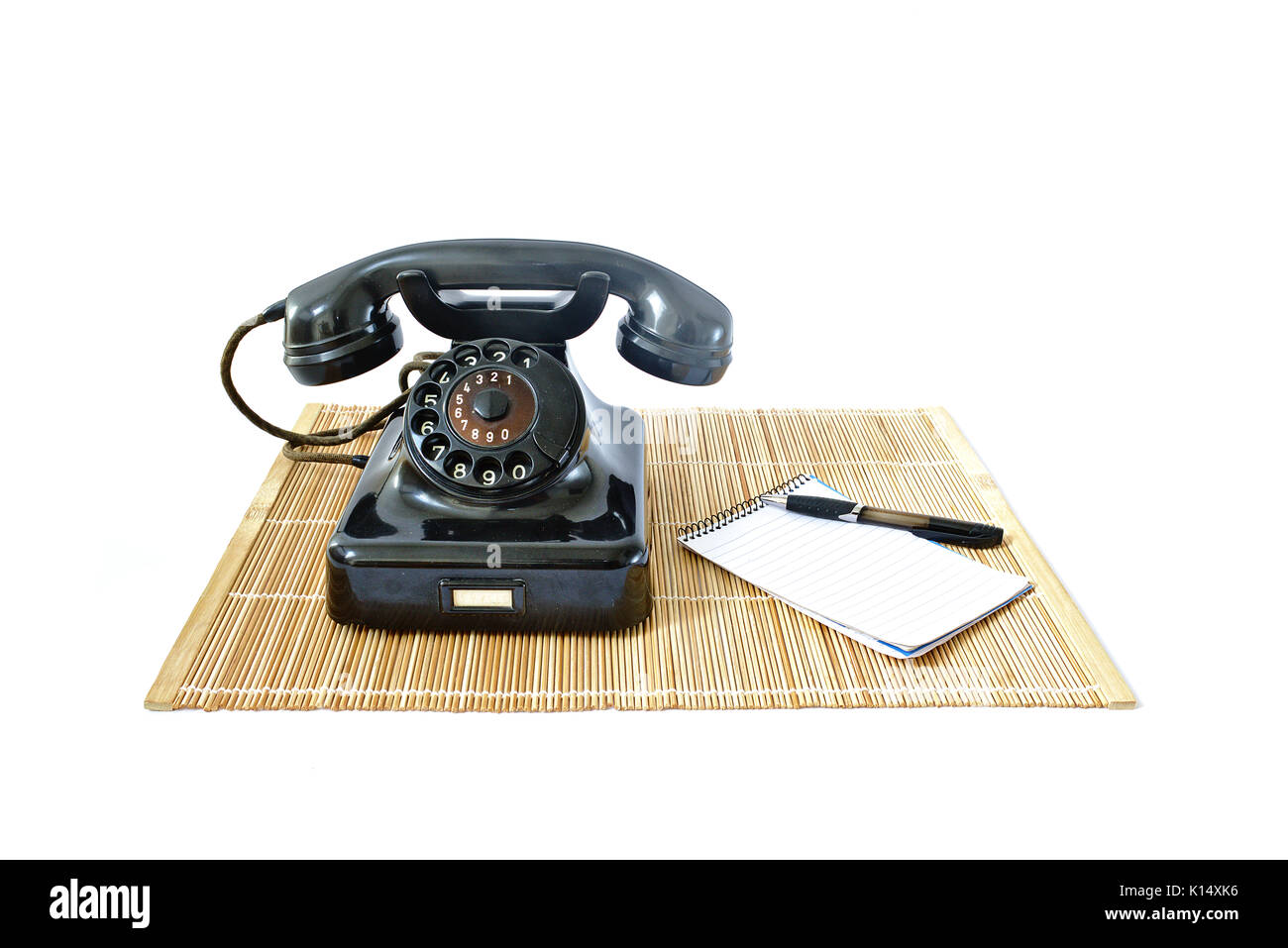 Vintage telephone on rattan mat with black pen and notepad with ...