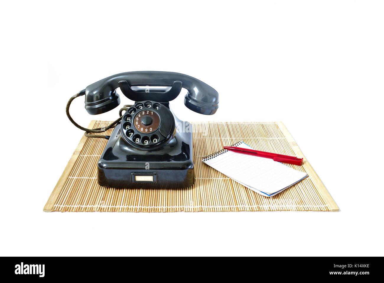 Vintage telephone on rattan mat with red pen and notepad with copyspace ...