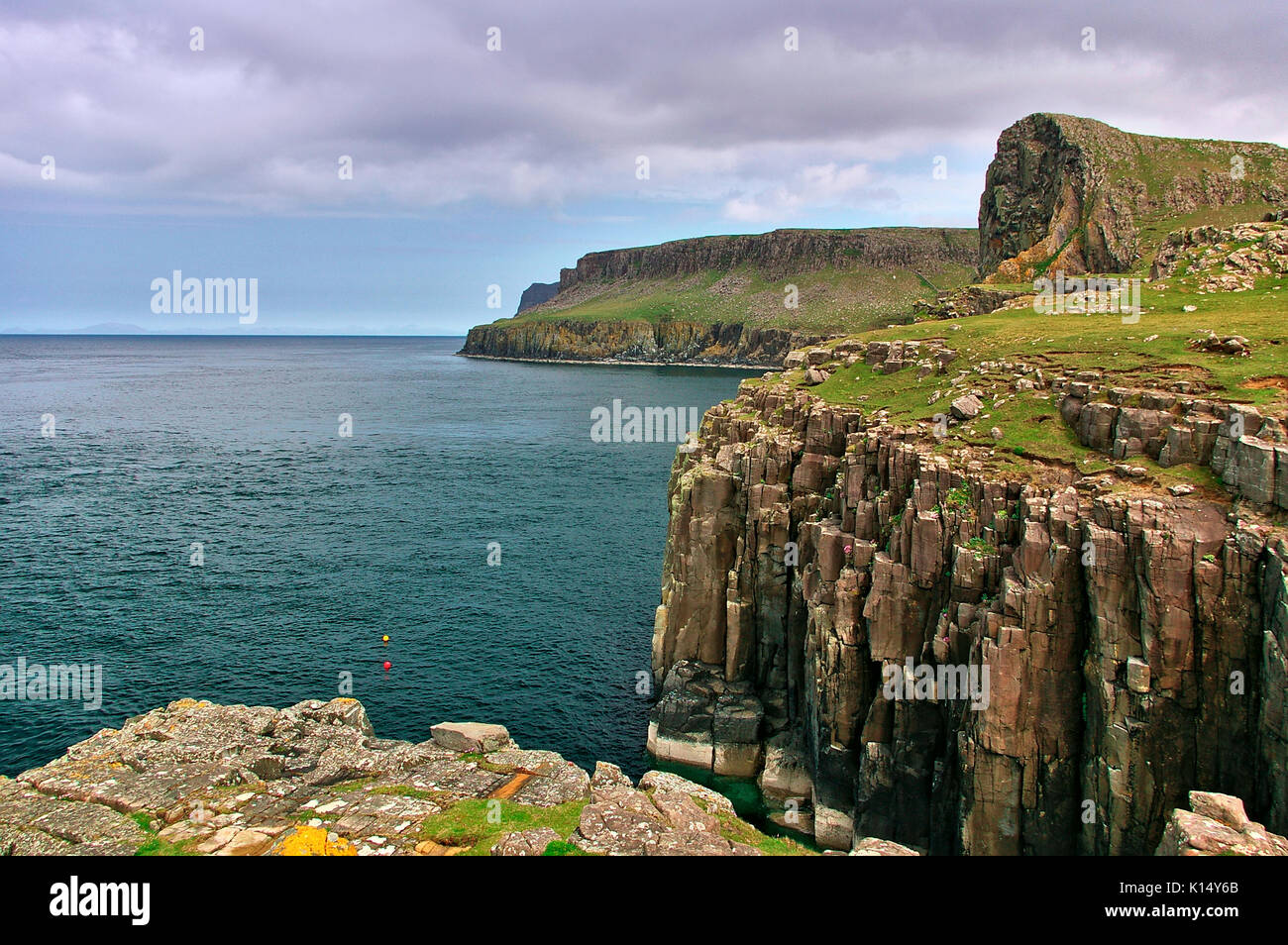 Steep rocky cliffs above the sea with mountains towering in the ...